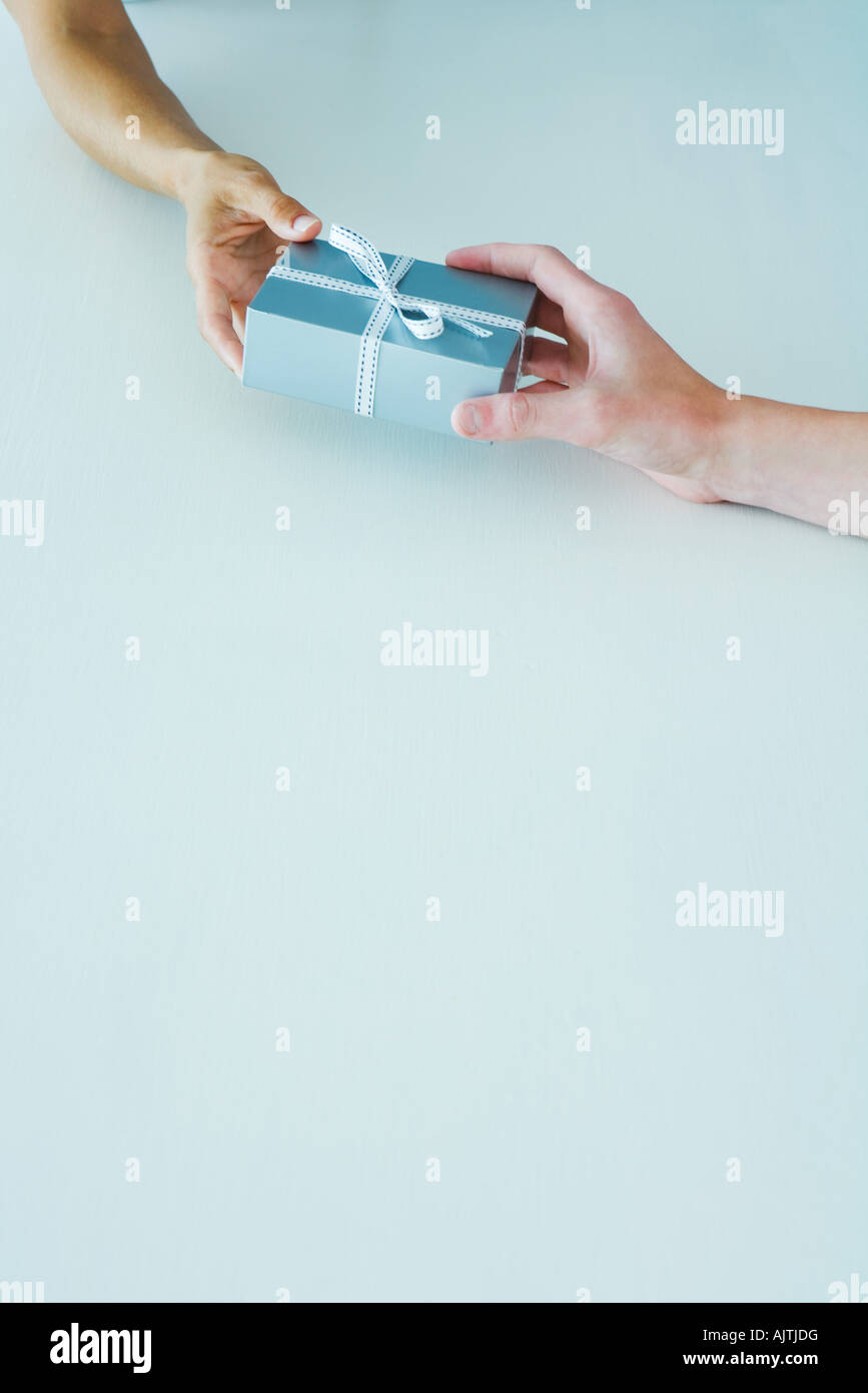 Gift giving, cropped view of two hands holding present between them ...