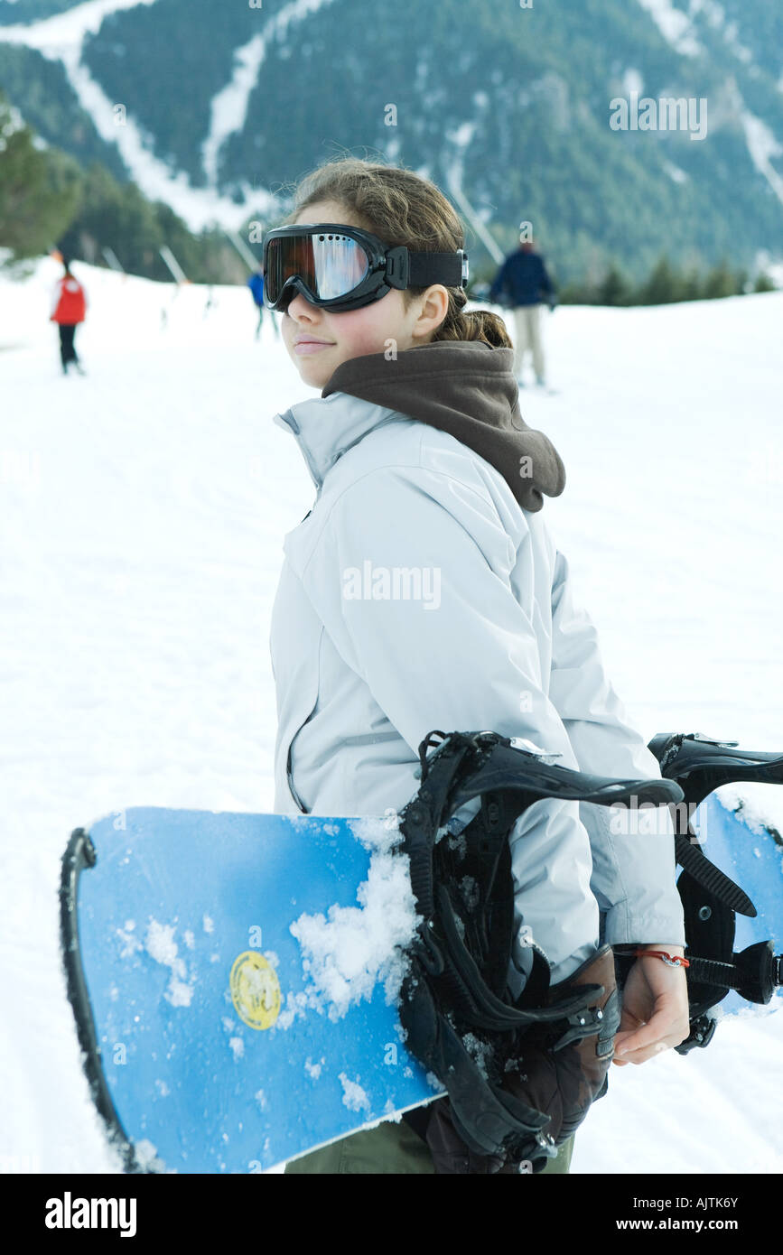 Teenage girl carrying snowboard behind back, waist up Stock Photo - Alamy