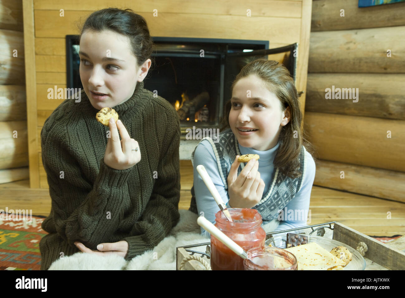 Teen girls having snack by fire place Stock Photo - Alamy