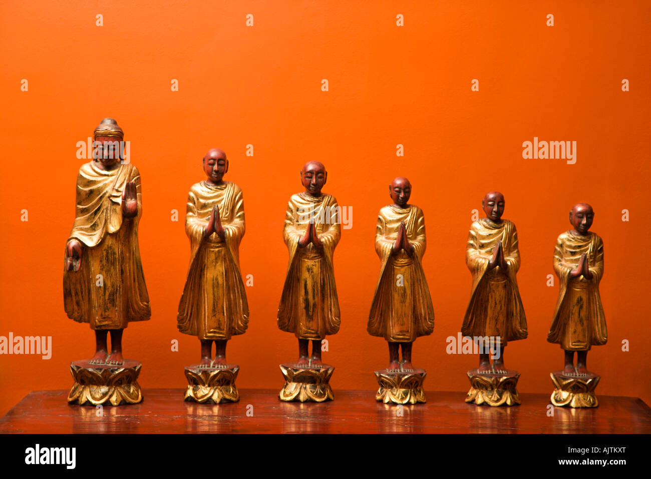 Wooden statues of Buddha with five disciples against orange wall Stock ...