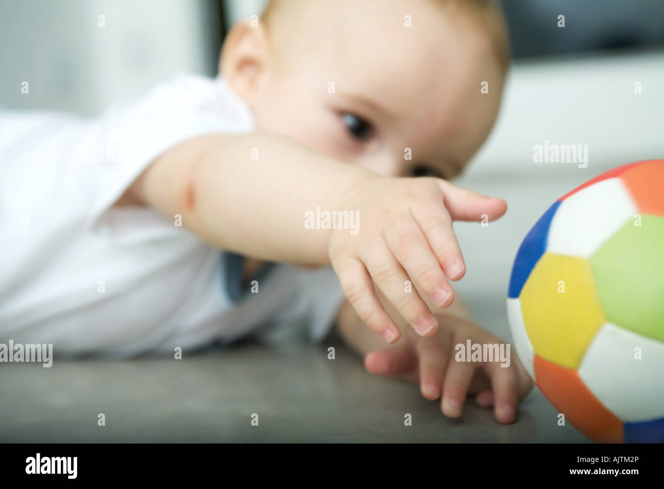 Baby on floor, reaching for ball Stock Photo - Alamy