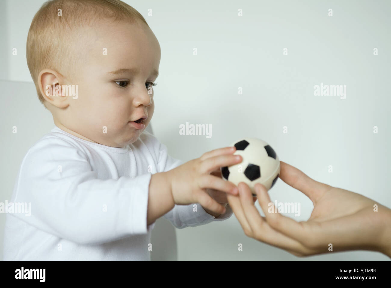 Baby taking ball from mother's hand, close-up Stock Photo - Alamy