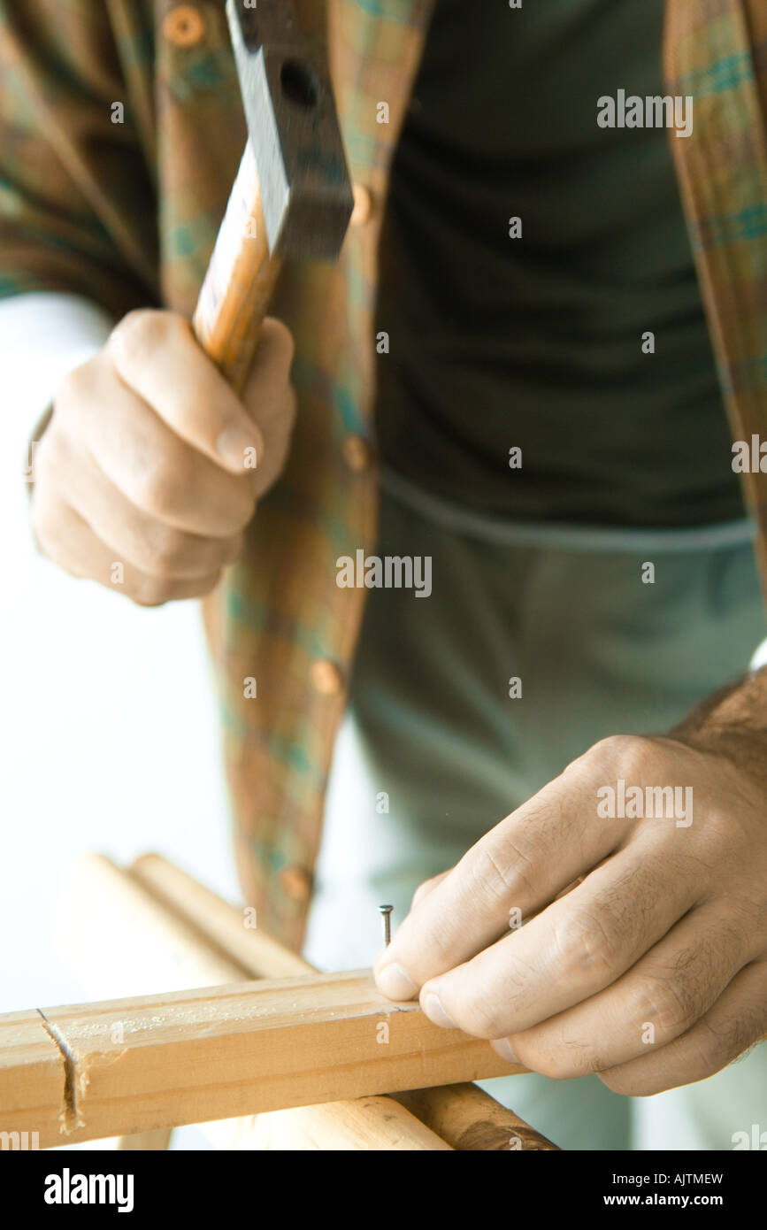 Man hammering nail into piece of wood, close-up of hands Stock Photo ...