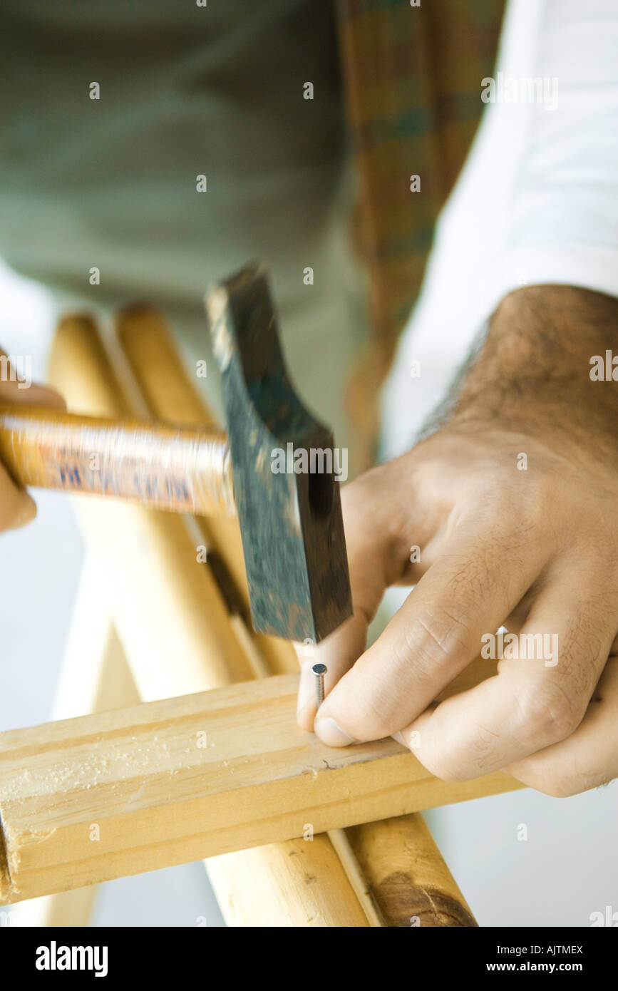 Man hammering nail into piece of wood, close-up of hands Stock Photo ...