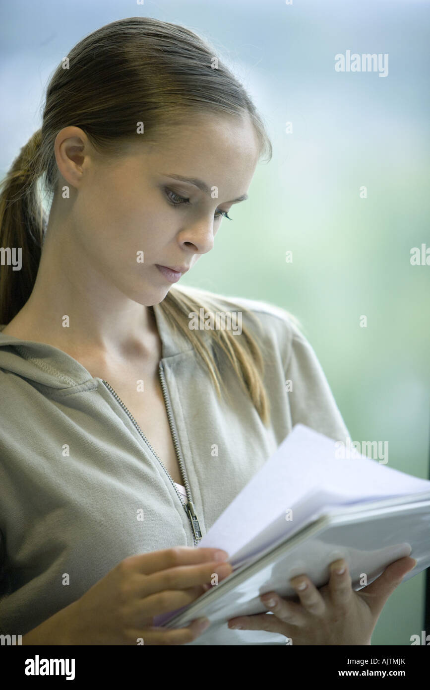 Female college student reading paper in binder, head and shoulders ...
