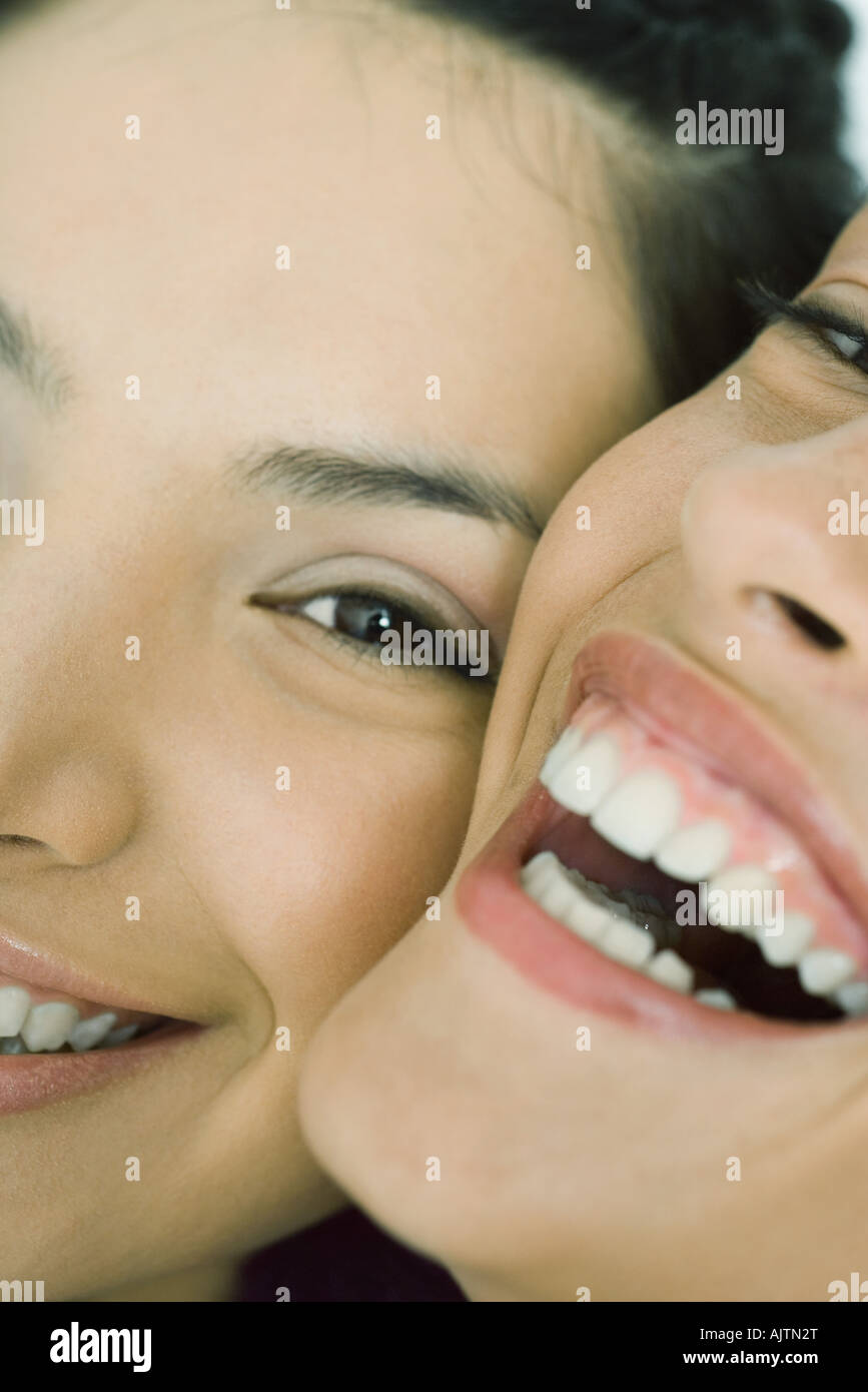 Cropped view of two young friends smiling at camera, cheek to cheek ...