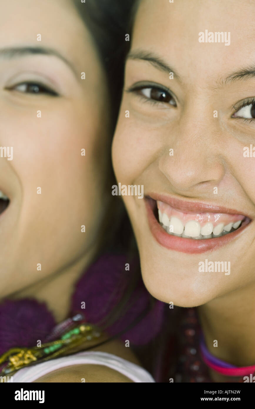Two young friends smiling at camera together, cheek to cheek, cropped ...