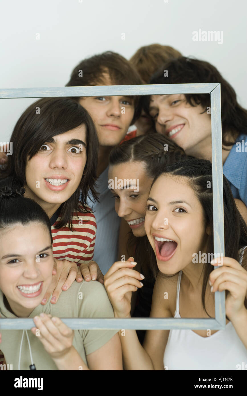 Young friends holding up frame together, smiling at camera Stock Photo ...