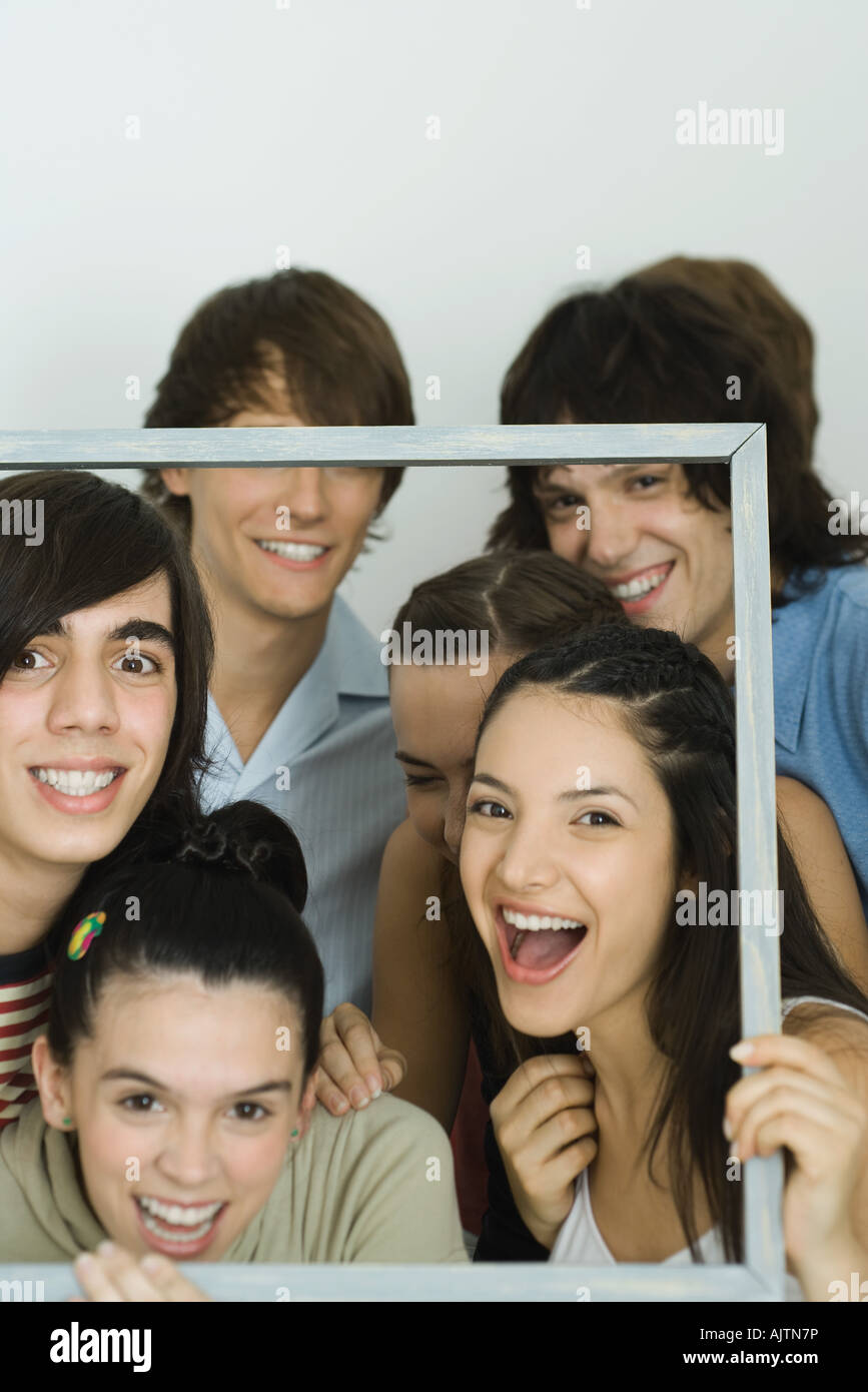 Young friends holding up frame together, smiling at camera Stock Photo ...