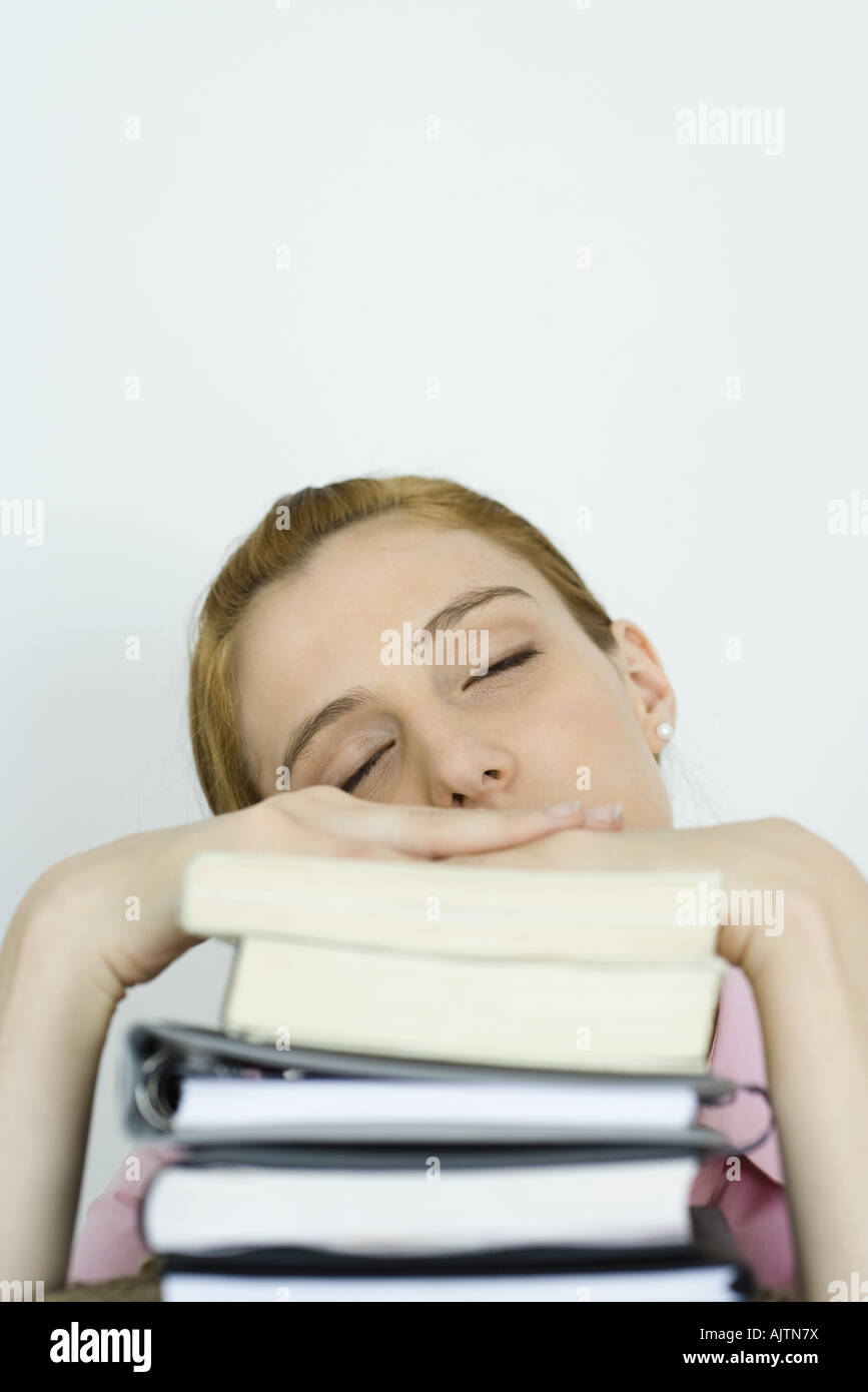 Young woman leaning on stack of books, eyes closed Stock Photo - Alamy