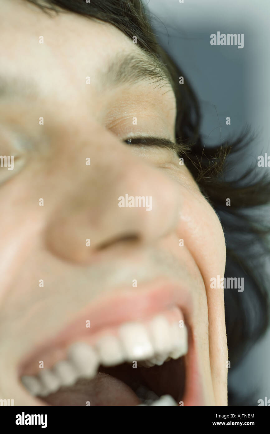 Cropped view of teenage boy laughing, eyes closed, extreme close-up ...