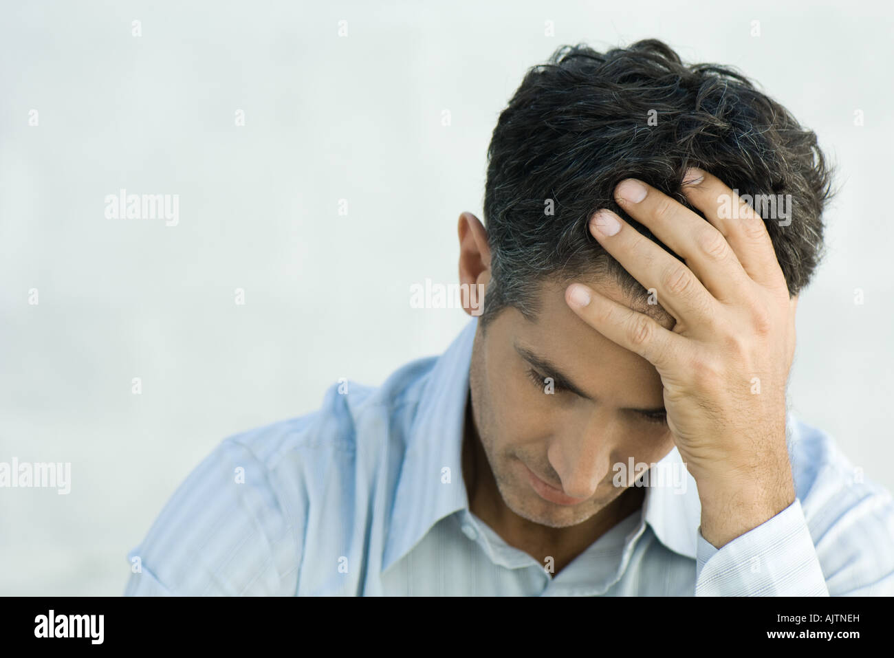 Mature man holding head, looking down Stock Photo - Alamy