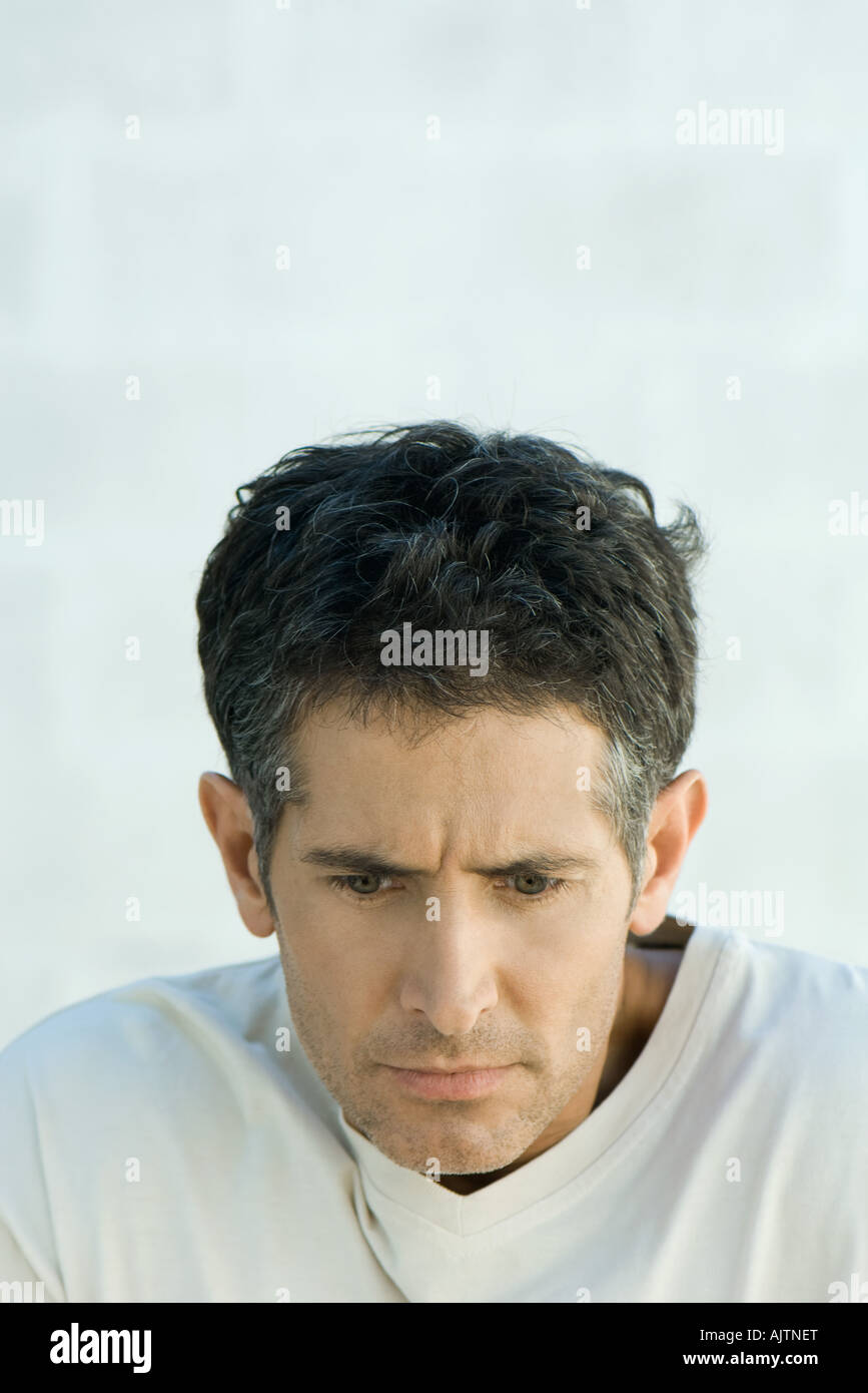 Mature man furrowing brow, looking down, portrait Stock Photo - Alamy
