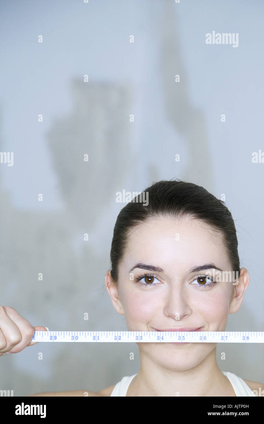 Young woman holding up tape measure, smiling at camera, portrait Stock ...