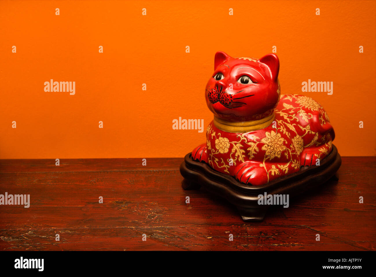 Chinese red cat statue against orange wall Stock Photo - Alamy