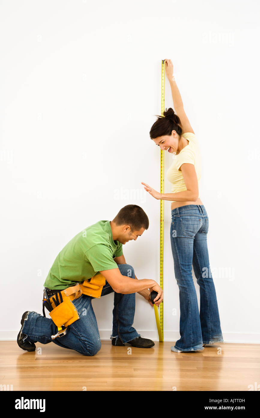 Couple measuring interior wall and smiling Stock Photo - Alamy
