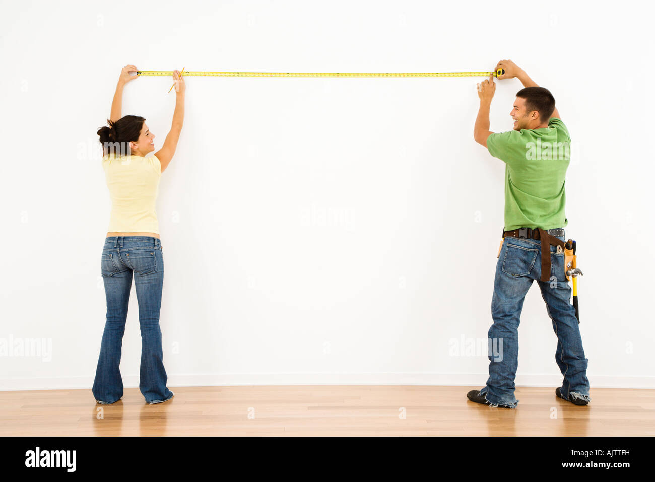 Couple measuring interior wall and smiling Stock Photo - Alamy