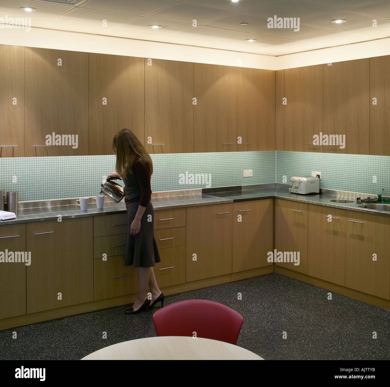 Office life and Interiors Part Two. Woman making tea in kitchen Stock ...