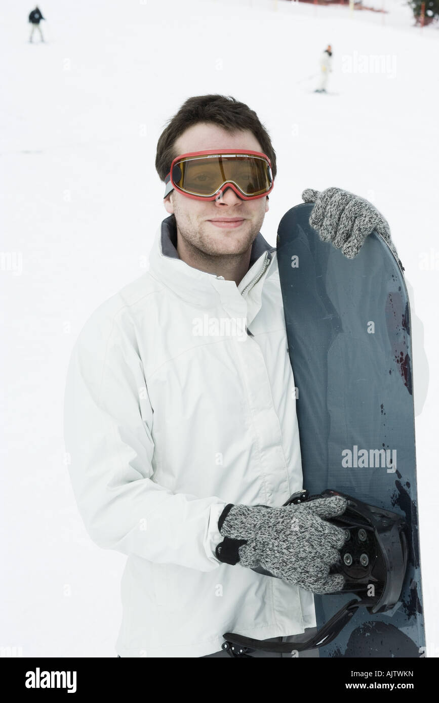 Young man standing with snowboard, portrait Stock Photo - Alamy