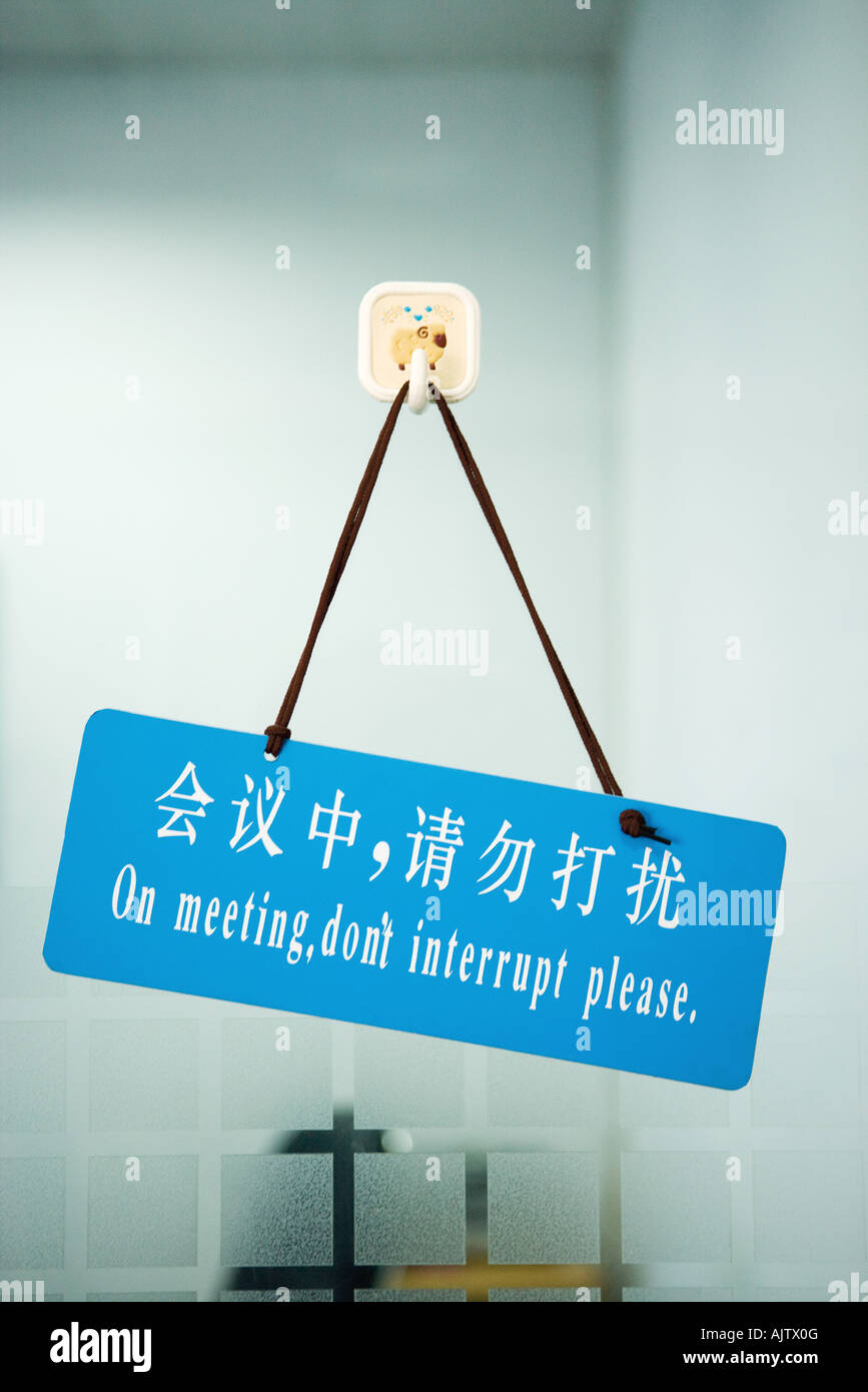 Bi-lingual sign on door stating "On meeting, don't interrupt please ...