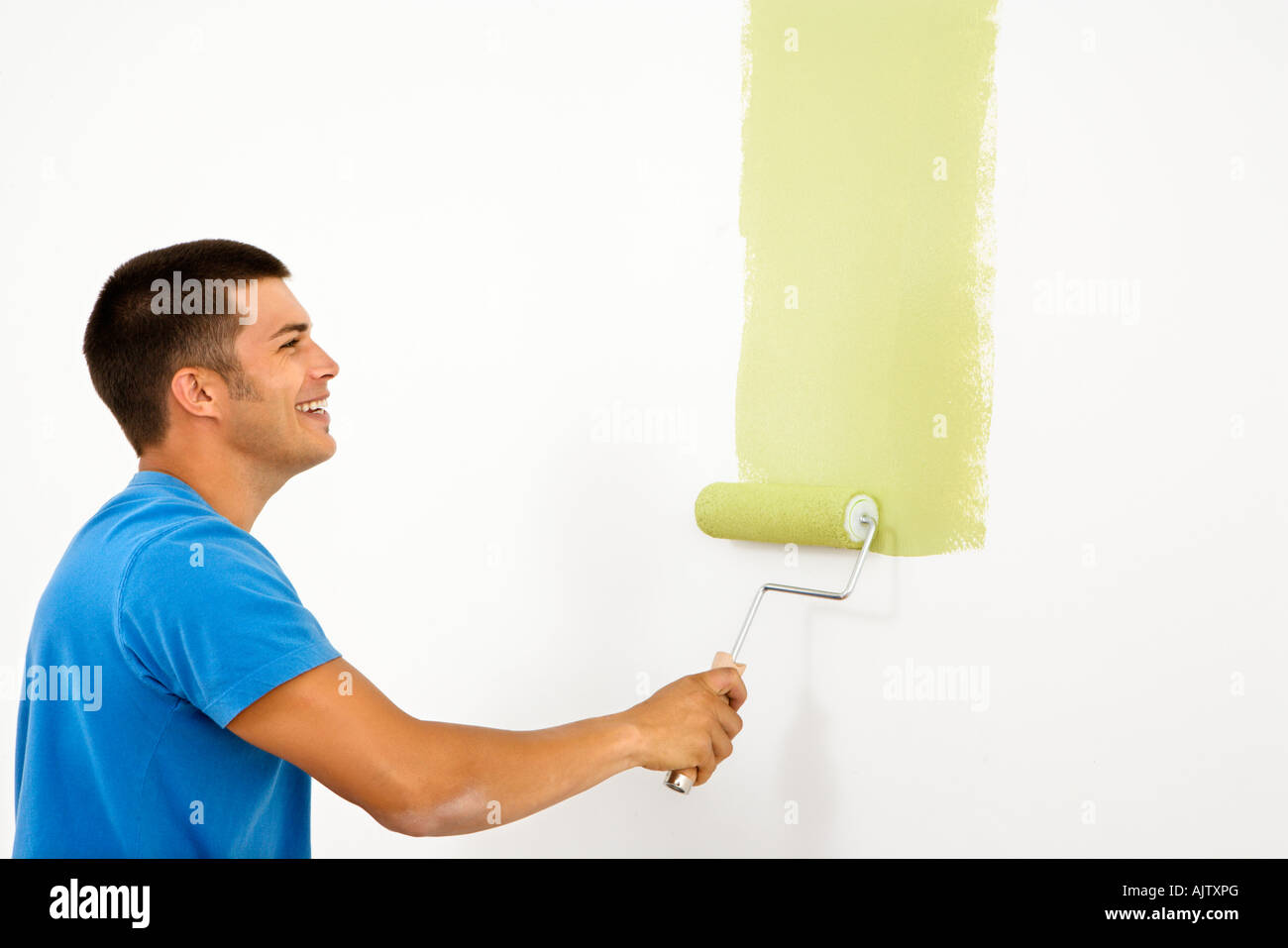 Attractive smiling man painting white wall with green paint Stock Photo ...