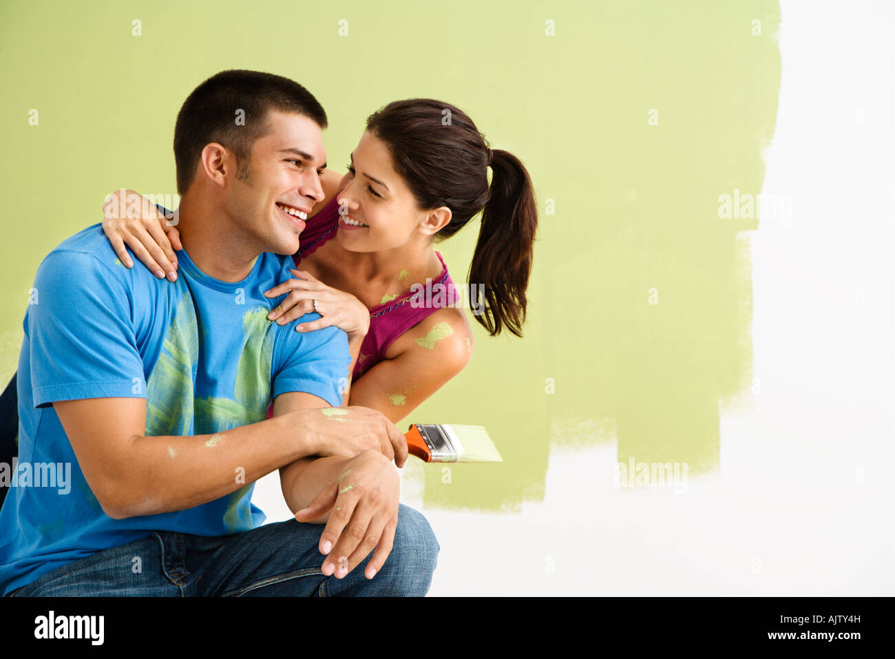 Couple smiling and laughing while painting interior wall of home Stock ...