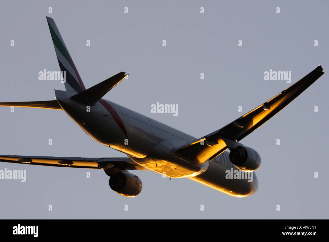 Emirates Boeing 777 just after take off in reflecting sunset light at ...