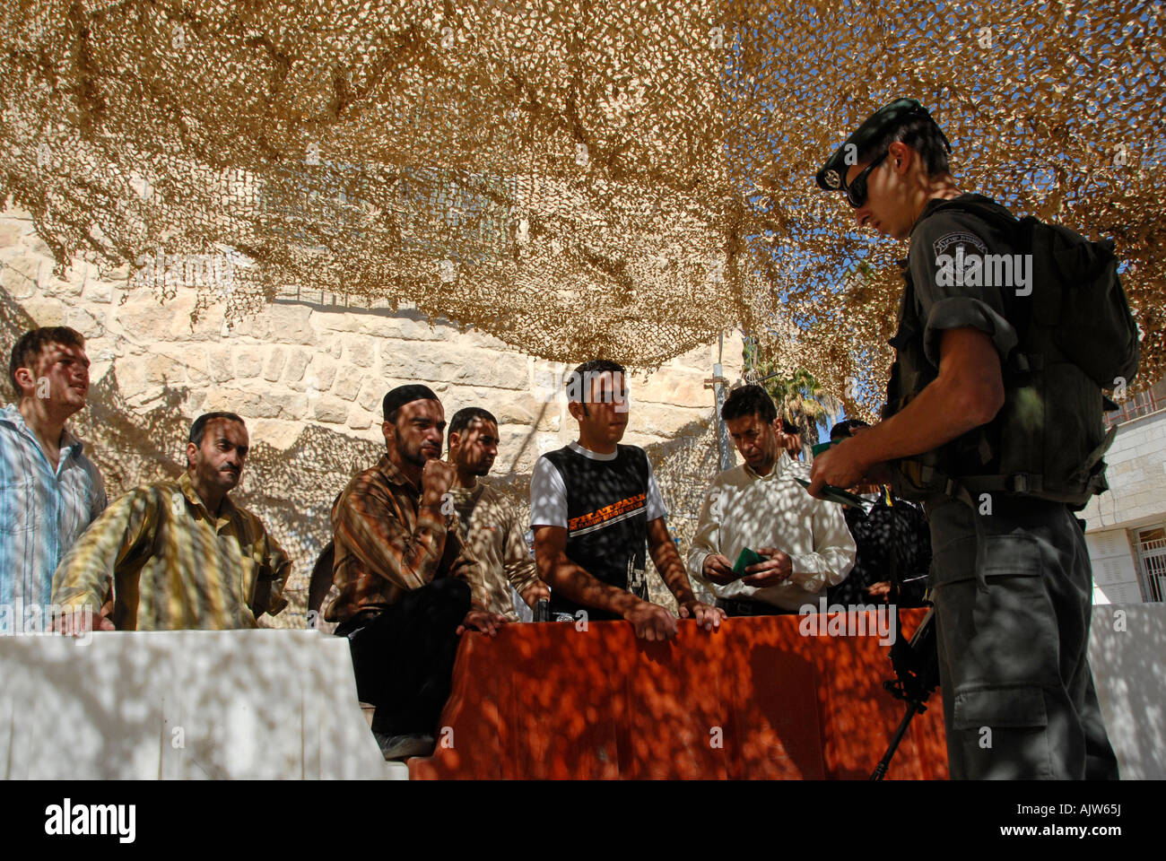 Israeli soldier checks ID of Palestinians at a checkpoint in n Al-Sahla ...