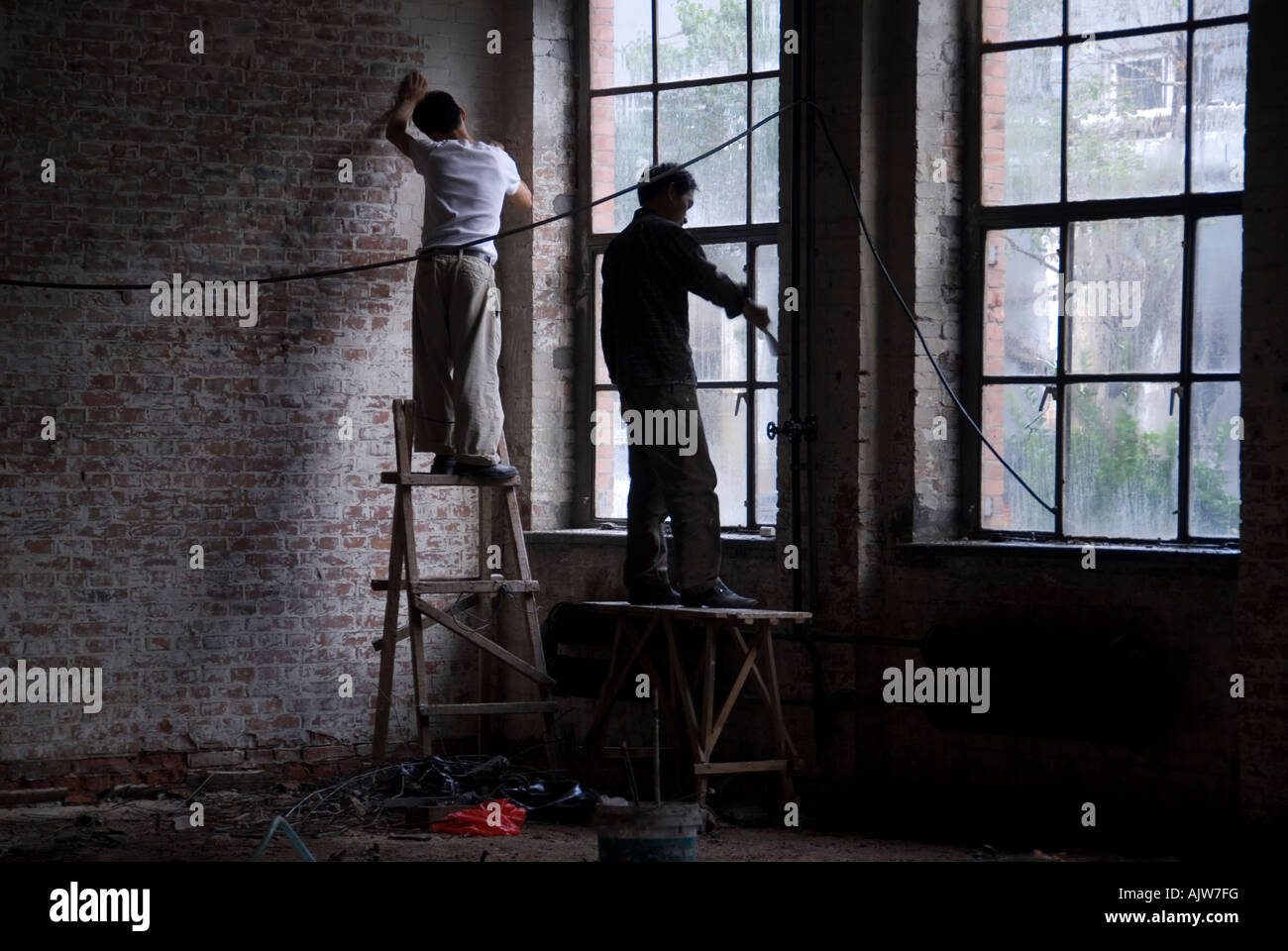 Chinese workmen renovate a building in an area of Beijing that is ...