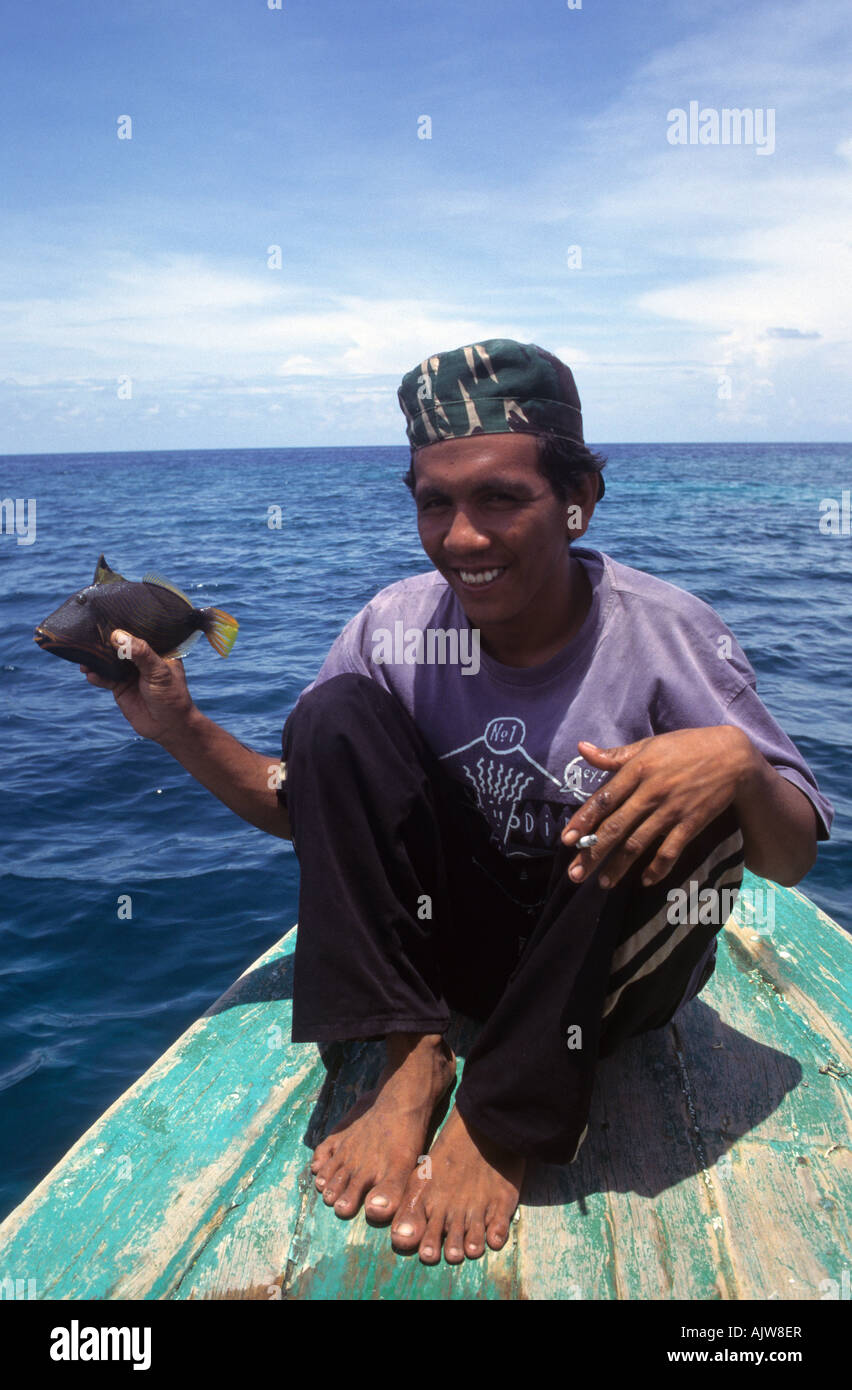 Fisherman smiling with a triggerfish on one hand and a cigarette on the ...