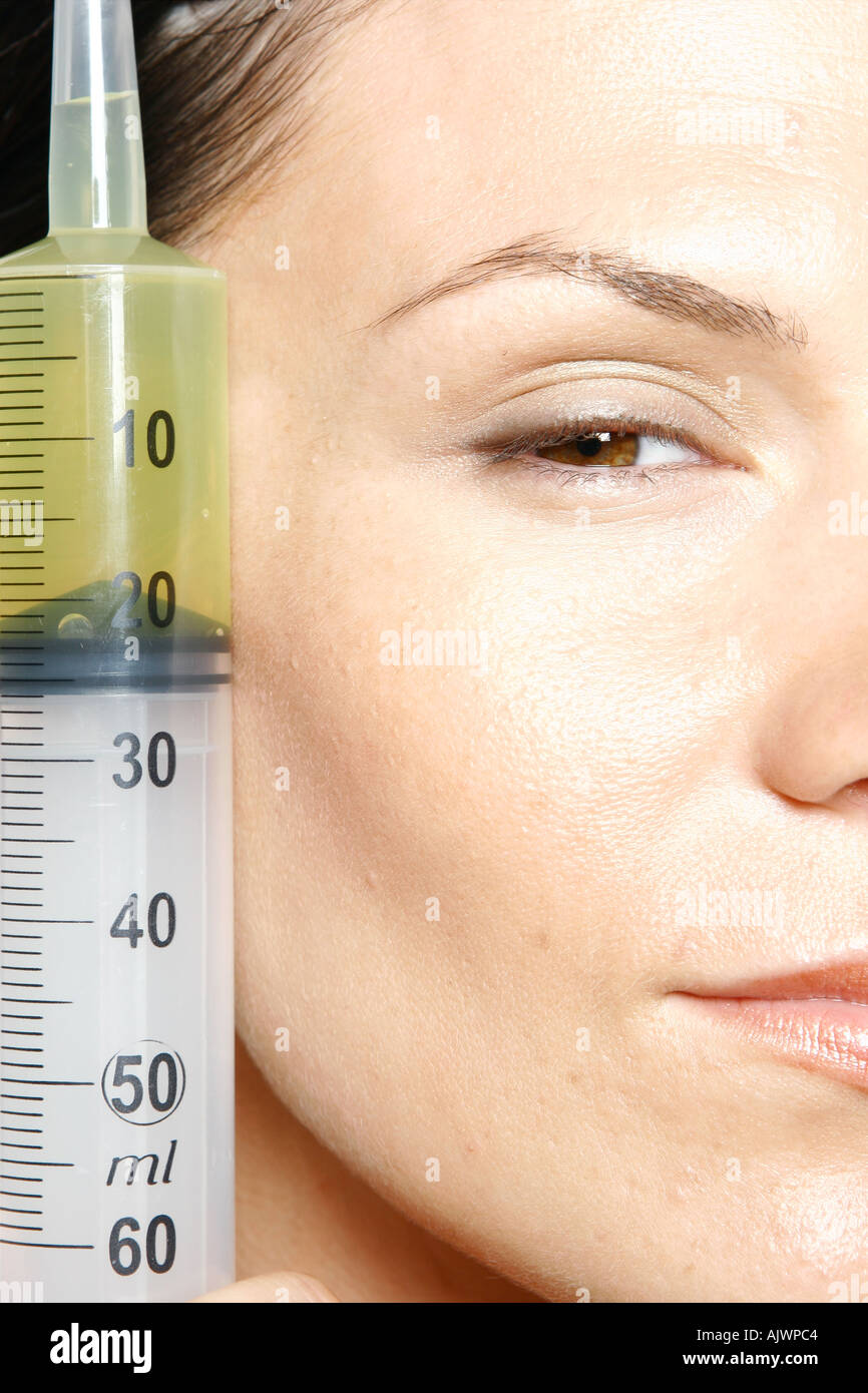 Woman holding syringe by her face, looking at camera Stock Photo - Alamy