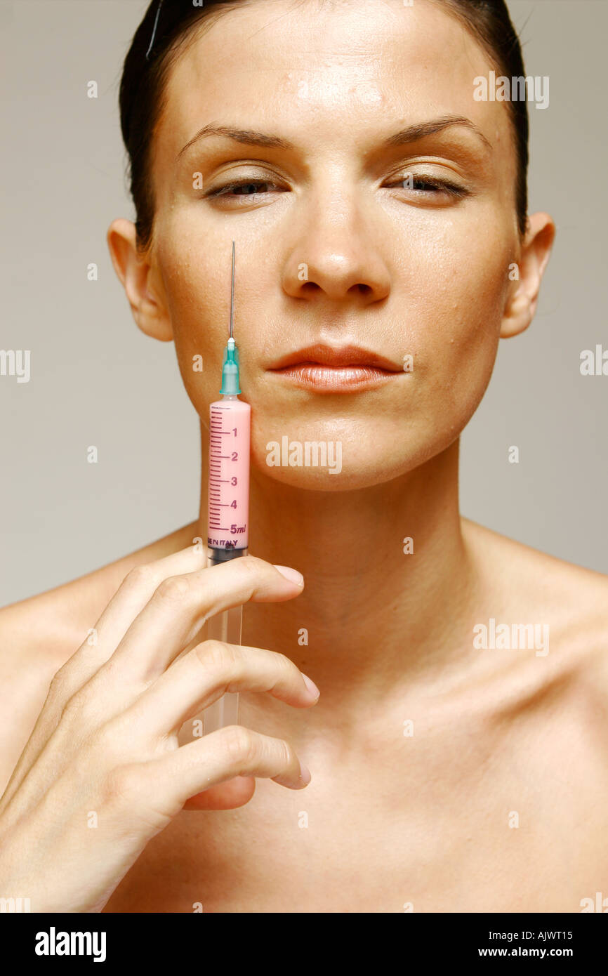 woman holding syringe by her face Stock Photo - Alamy