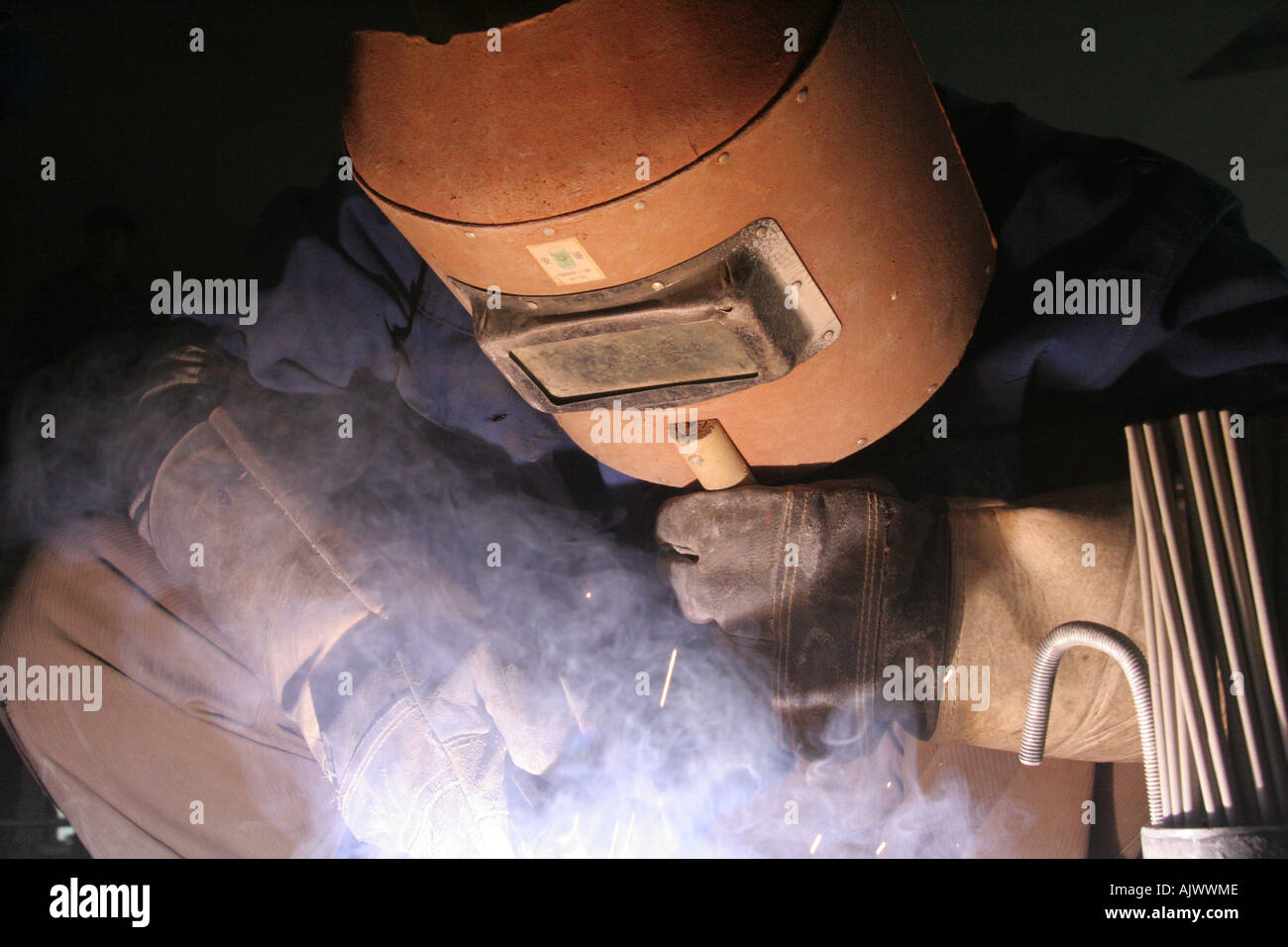 A Chinese construction worker welding metal joints in a skyscraper ...