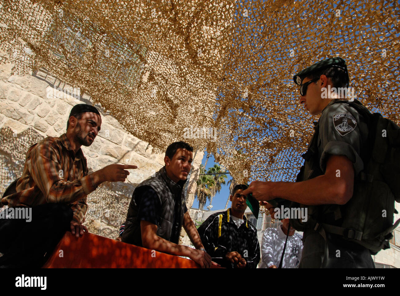 Israeli soldier checks ID of Palestinians at a checkpoint in n Al-Sahla ...