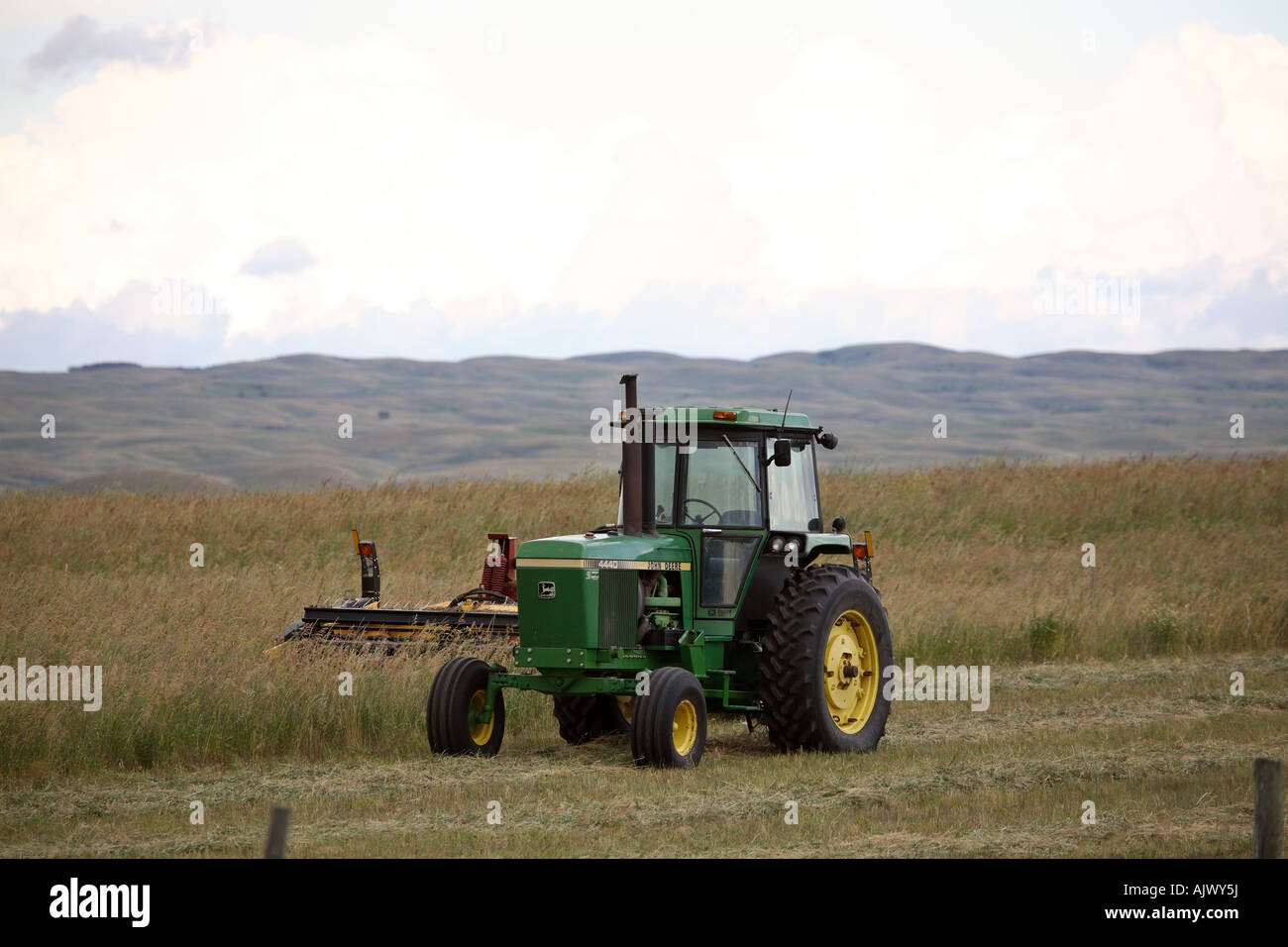Idle tractor and mower in hay field Stock Photo - Alamy