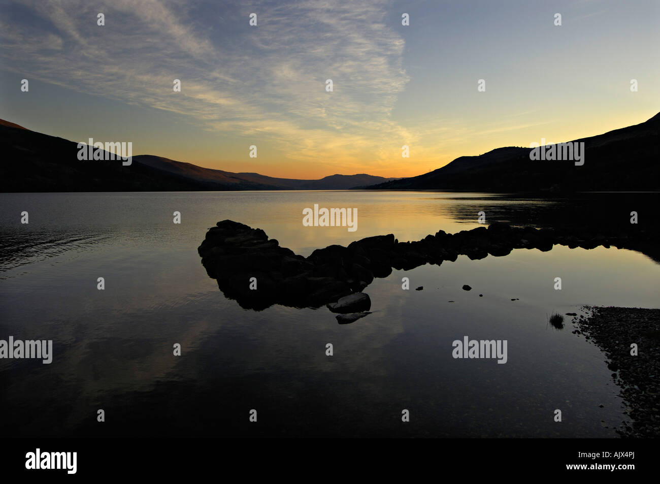 Sunset over calm water of Loch Tay and distant black hills, Scotland ...