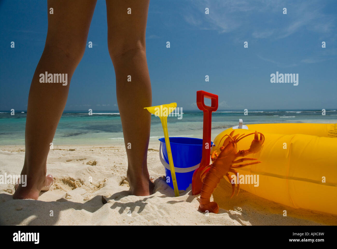 Girl standing on tropical white sandy beach with beach toys in ...