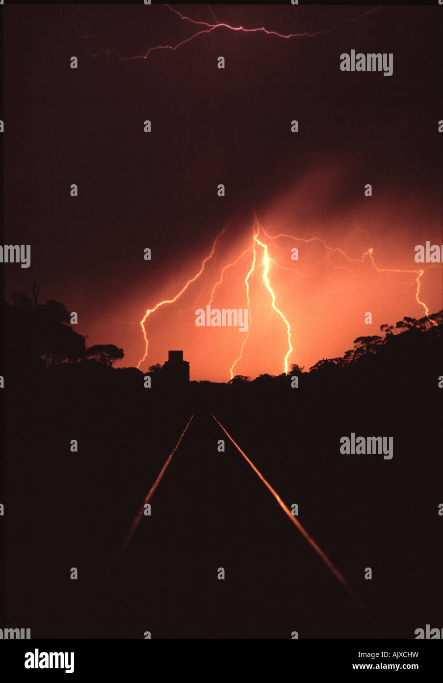 Fork lightning striking over railway track at night Stock Photo - Alamy