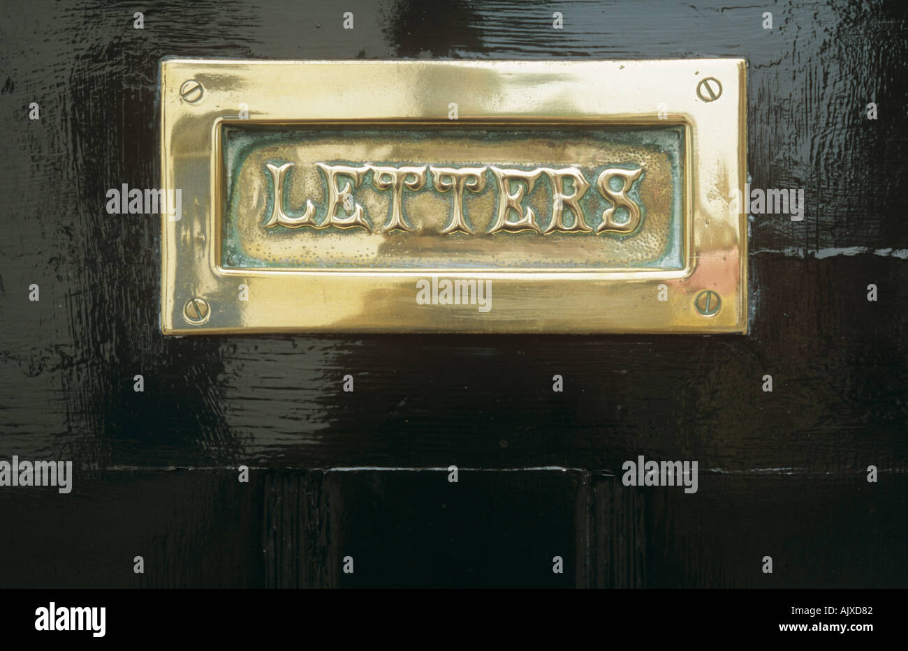 Polished brass letterbox in black front door Stock Photo - Alamy