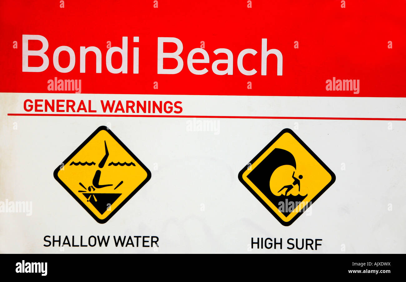 A sign warns tourists and visitors of shallow water and high surf at ...