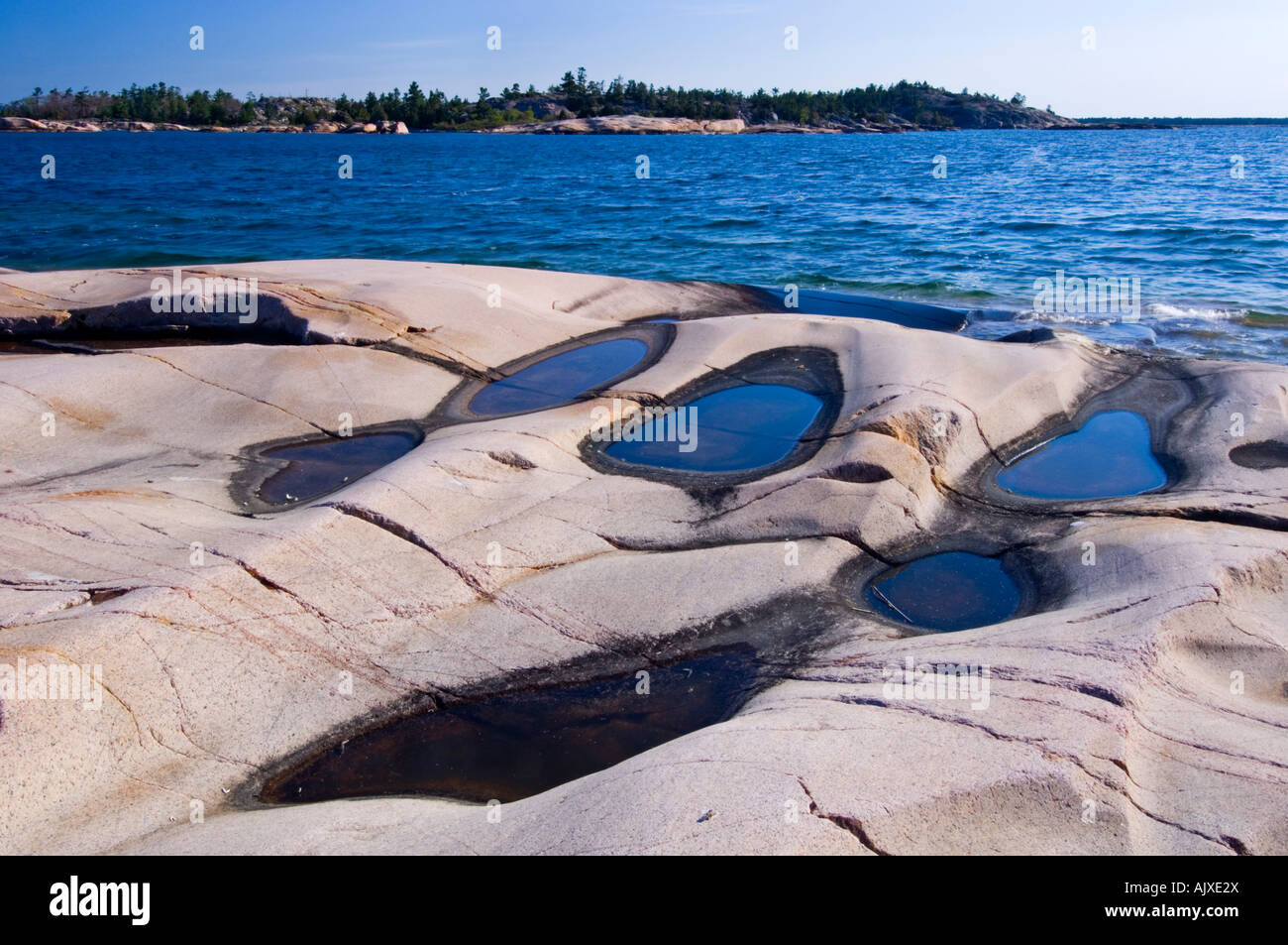 Weathered rocks and shallow pools along shore of small island in the ...