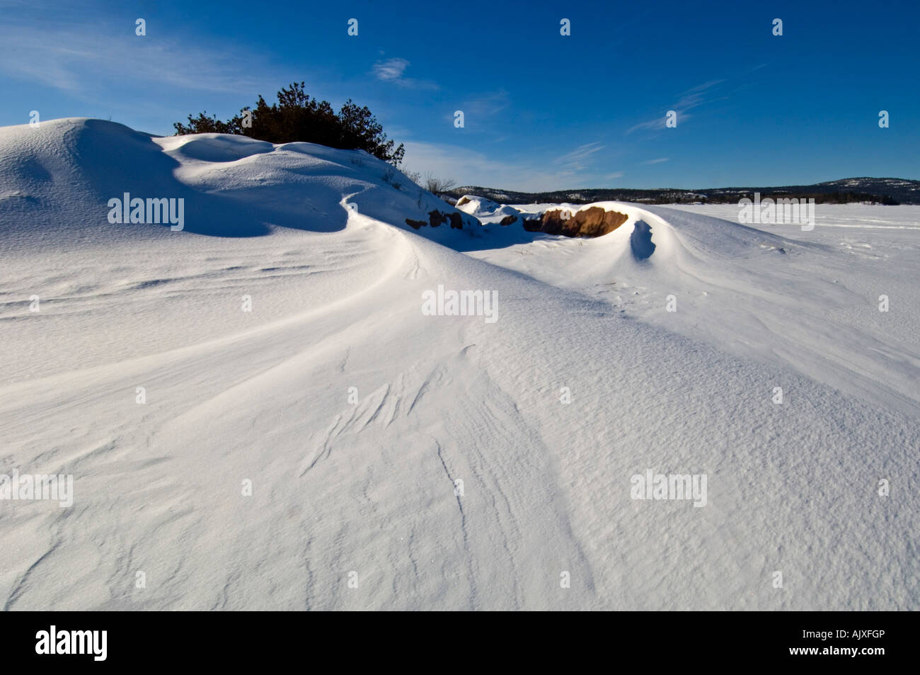 Wind-sculpted snow and small island in Lake Huron winter bay, Killarney ...