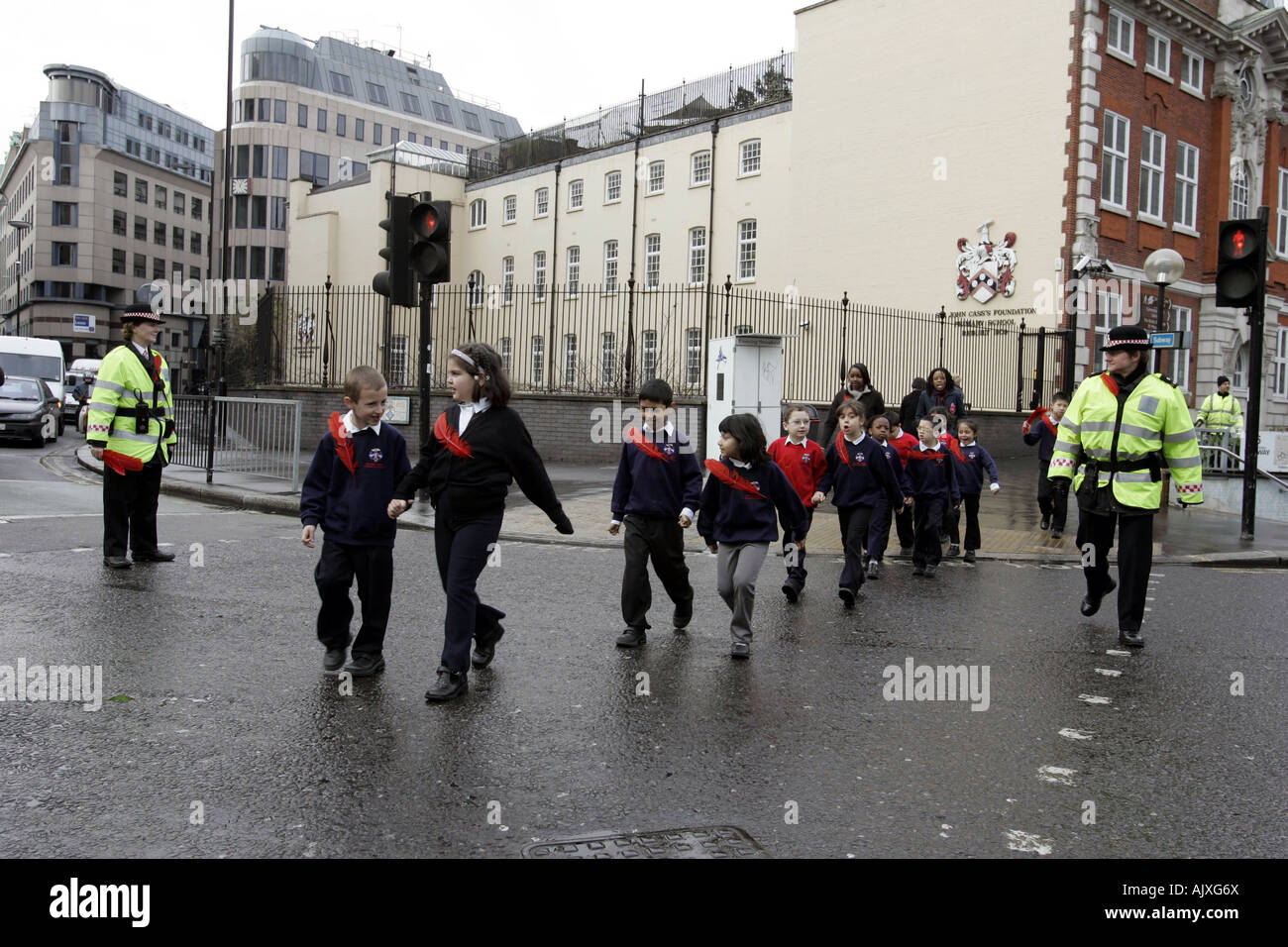 Schoolchildren crossing the road at traffic-light London England UK ...