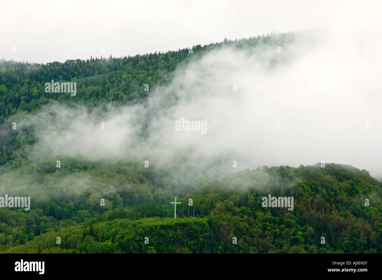 Fog-shrouded mountain slope with cross along St. Lawrence Gulf ...
