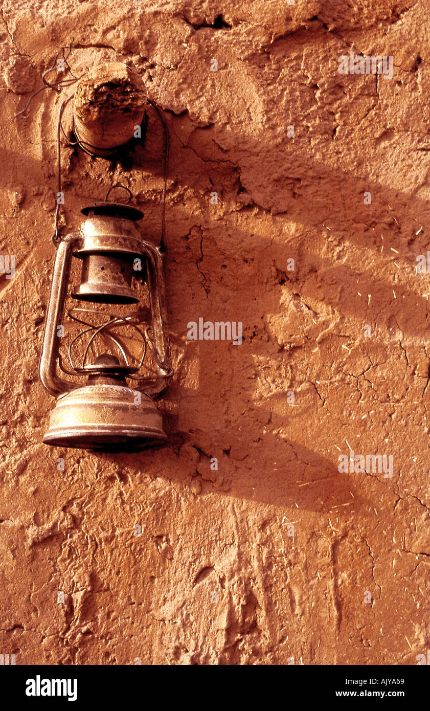 A broken oil lamp hangs outside an abandoned adobe hut in the Sahara ...