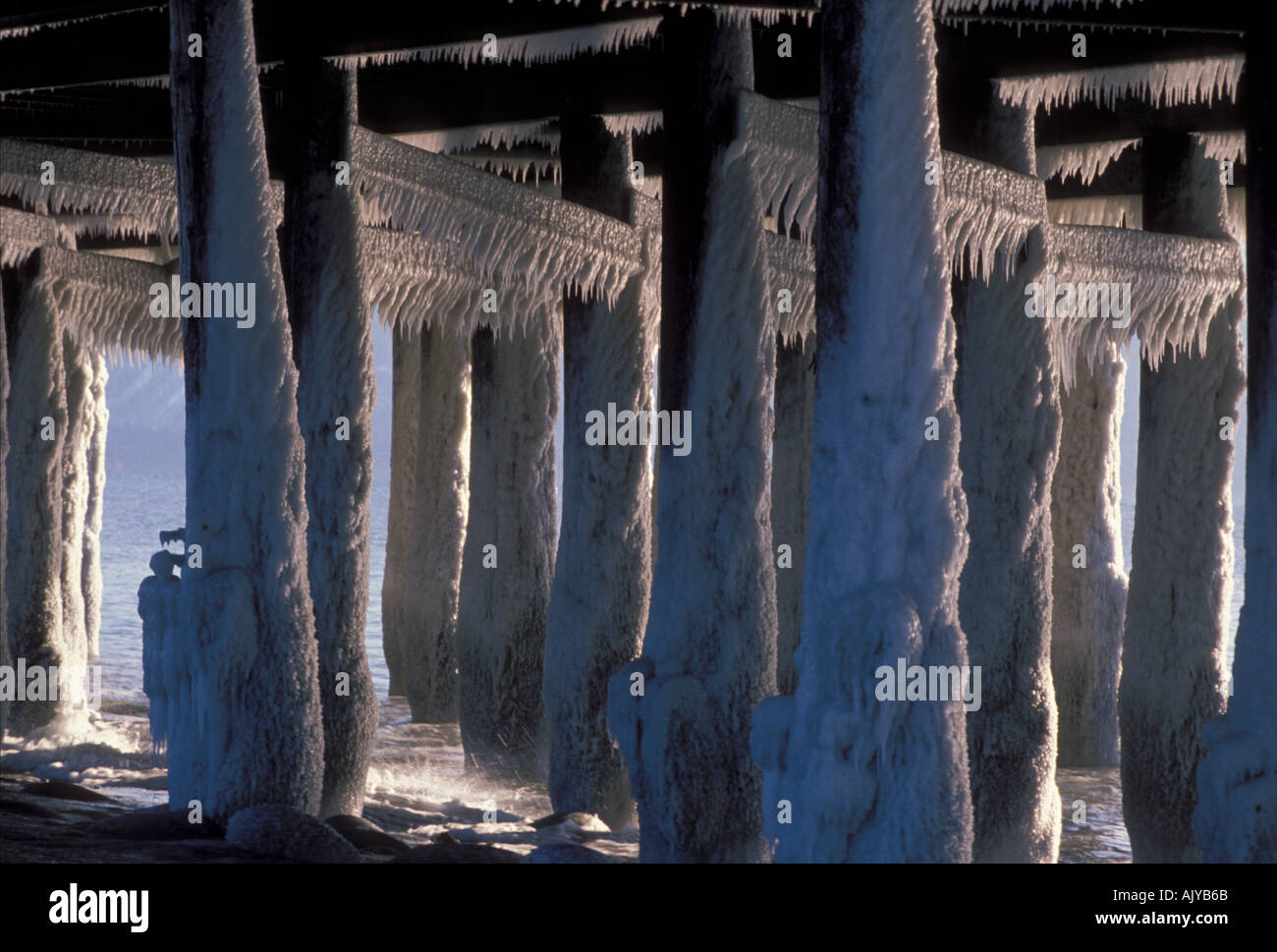 Pilings covered with ice from spray seawater at low ebb tide Homer Spit ...