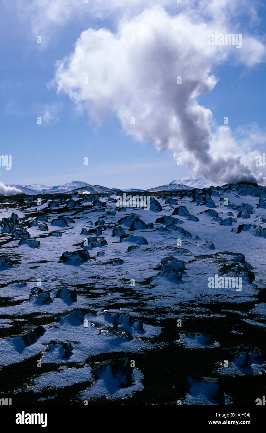 Steam rises from behind the snowy lava rocks near Myvatn Thermal Baths ...