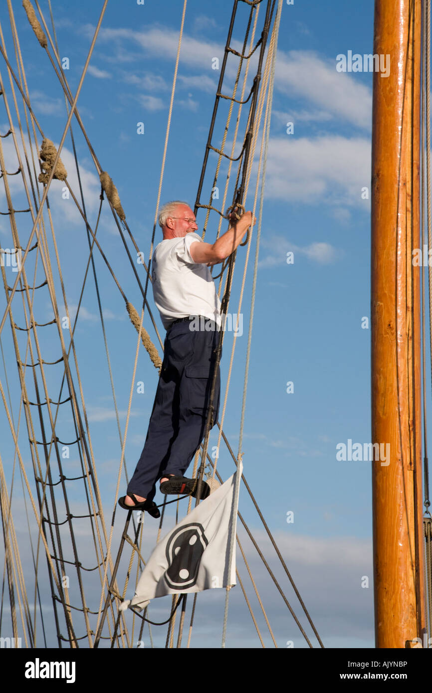 Sailor adjusting sails of a beautiful old style wooden sailboat- close ...