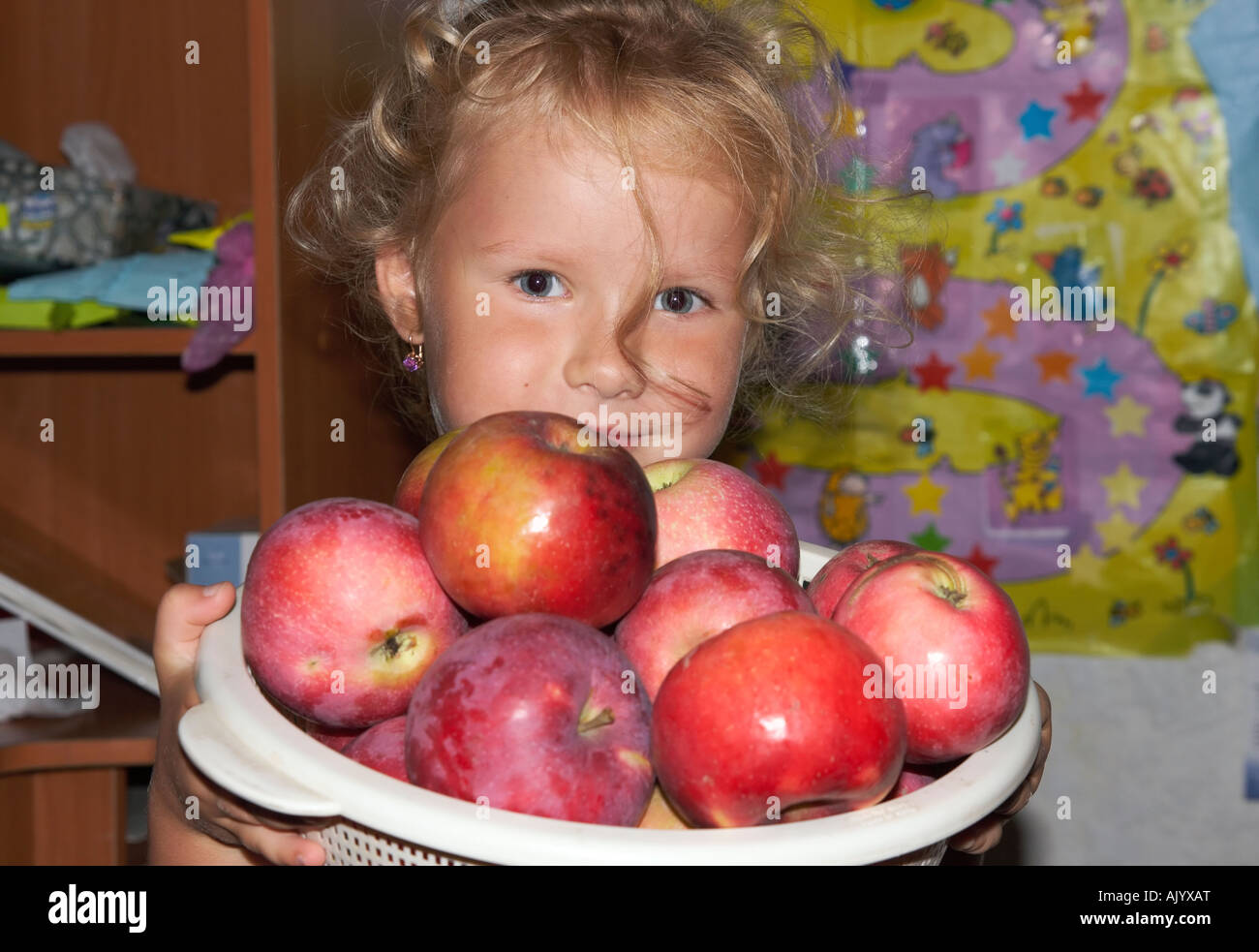 little girl with red apples in children room Stock Photo - Alamy