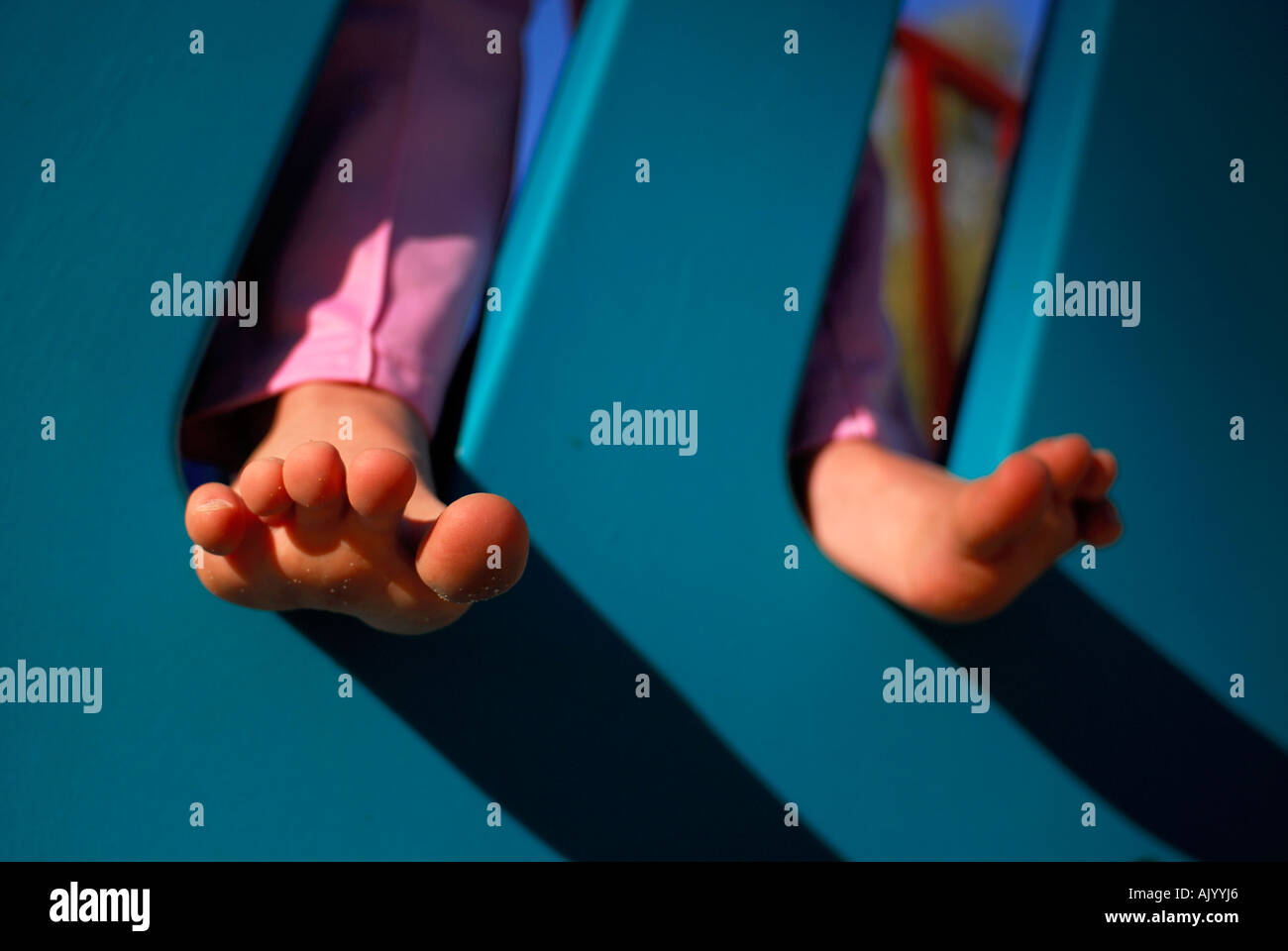 close up of young female child showing two feet and toes in playground ...